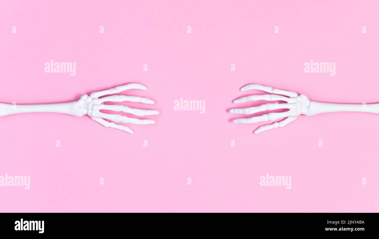 Creepy skeleton hands on pastel pink background. Flat lay copy space ...