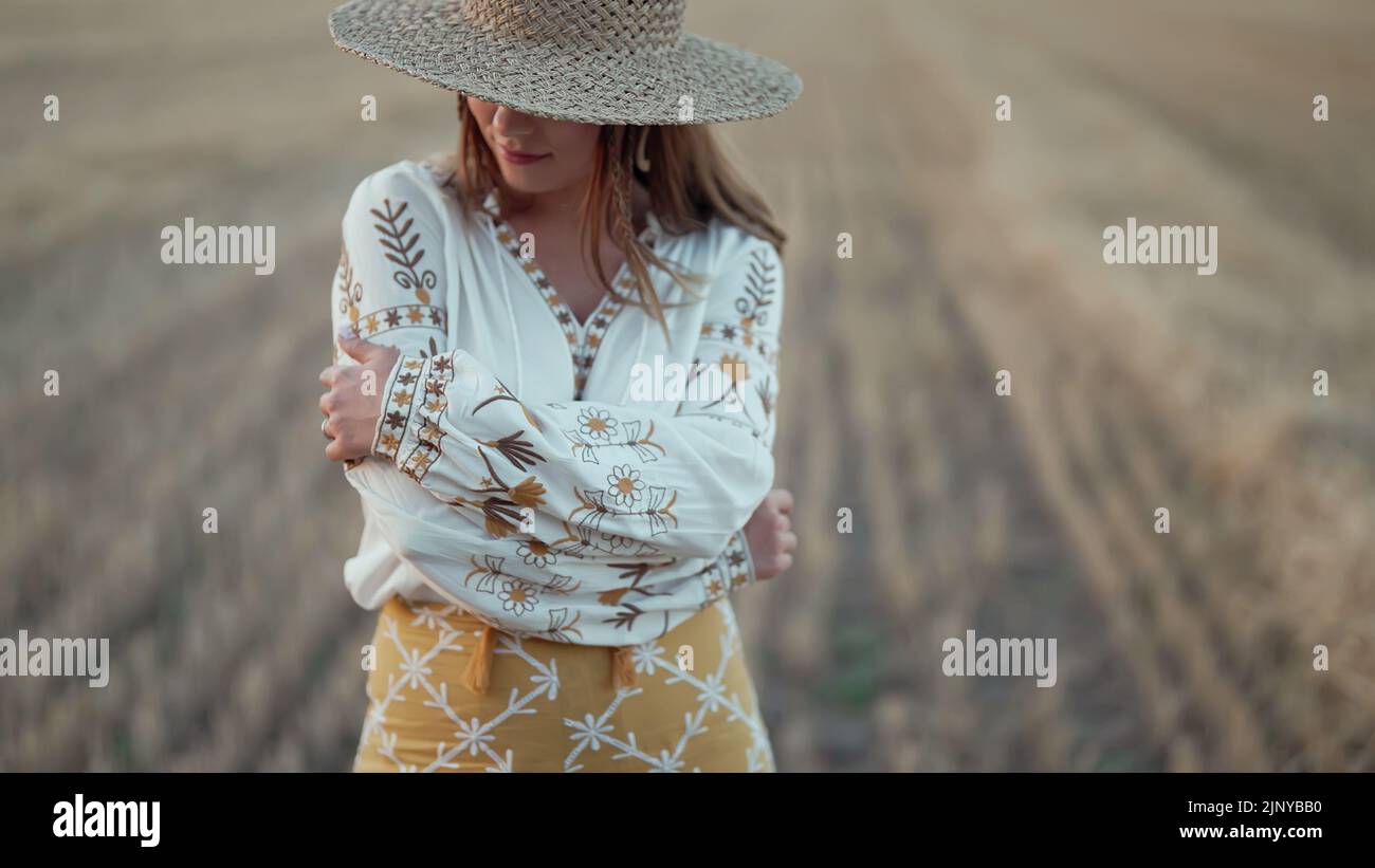 Ukrainian woman in traditional ethnic costume and straw hat in wheat ...