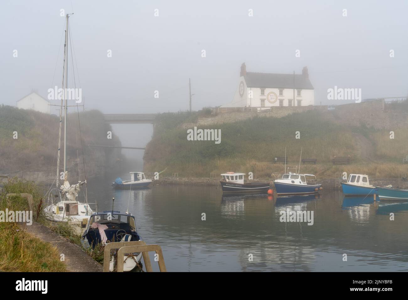 Boats in heavy sea fret at the harbour, at high tide in Seaton Sluice ...