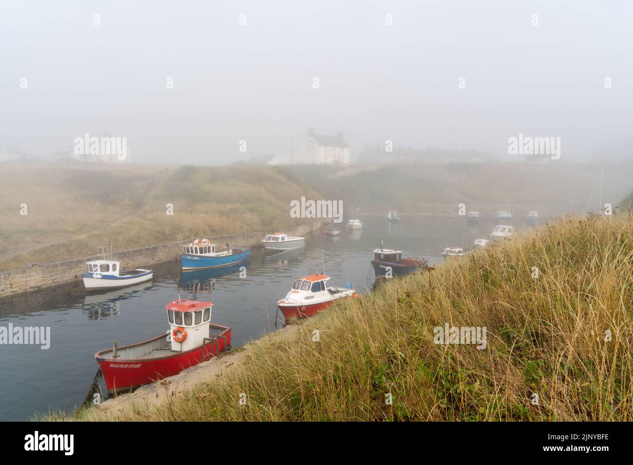 Boats in heavy sea fret at the harbour, at high tide in Seaton Sluice ...