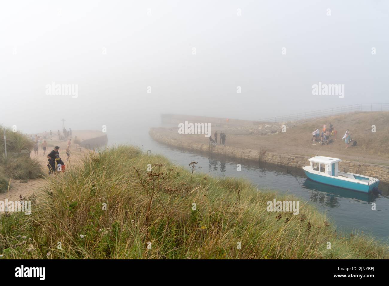 Boat in heavy sea fret at the harbour, at high tide in Seaton Sluice ...