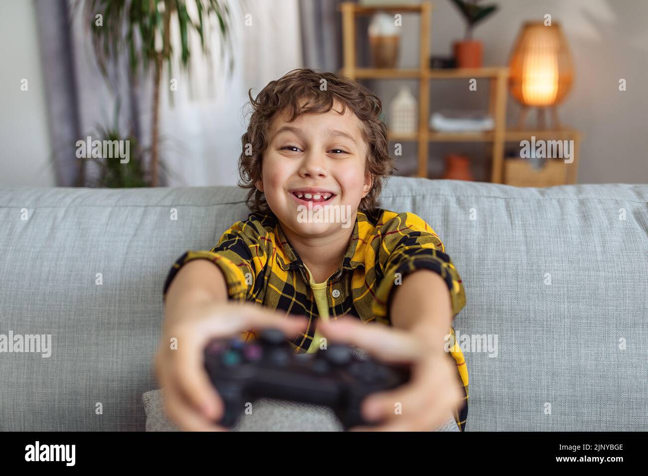 Close up portrait of emotional little boy playing video games on gamepad, pushing buttons on ...