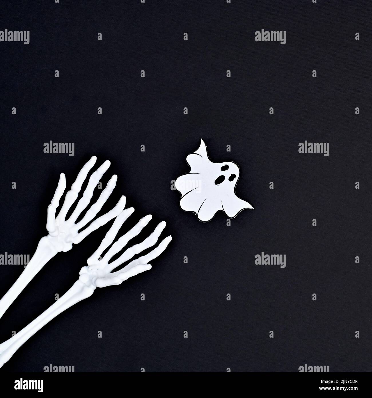 Creepy skeleton hands with ghost on dark black background. Halloween copy space flat lay concept ...