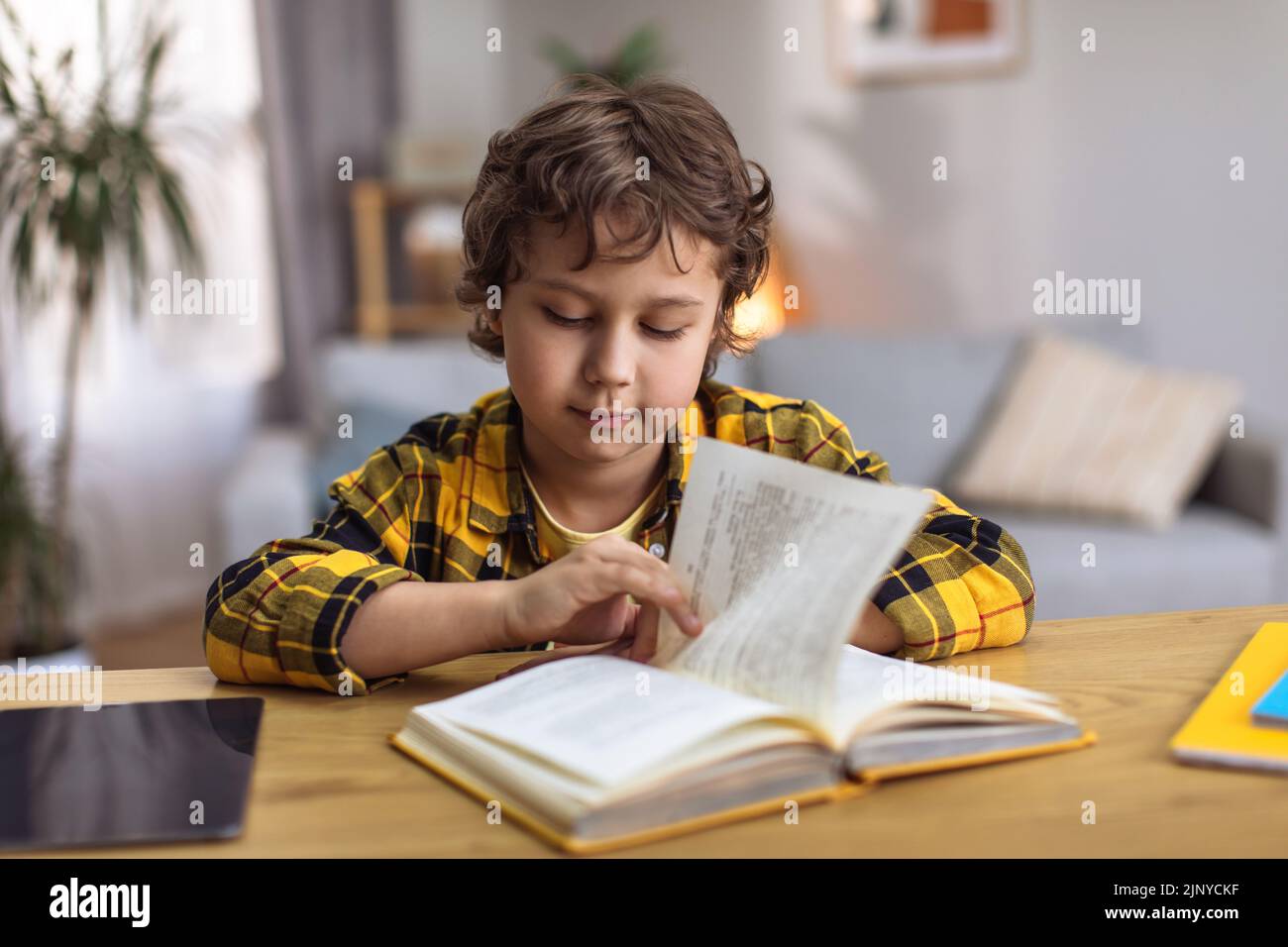 Domestic learning. Cute little boy study to read, reading book at desk ...