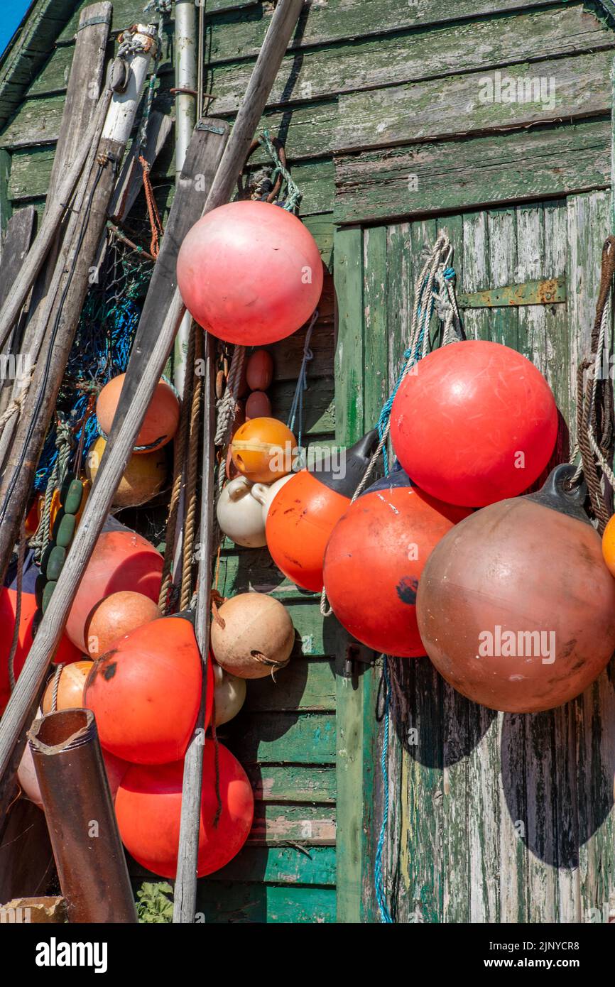 colourful fishing floats hanging on the side of a shabby old weather ...