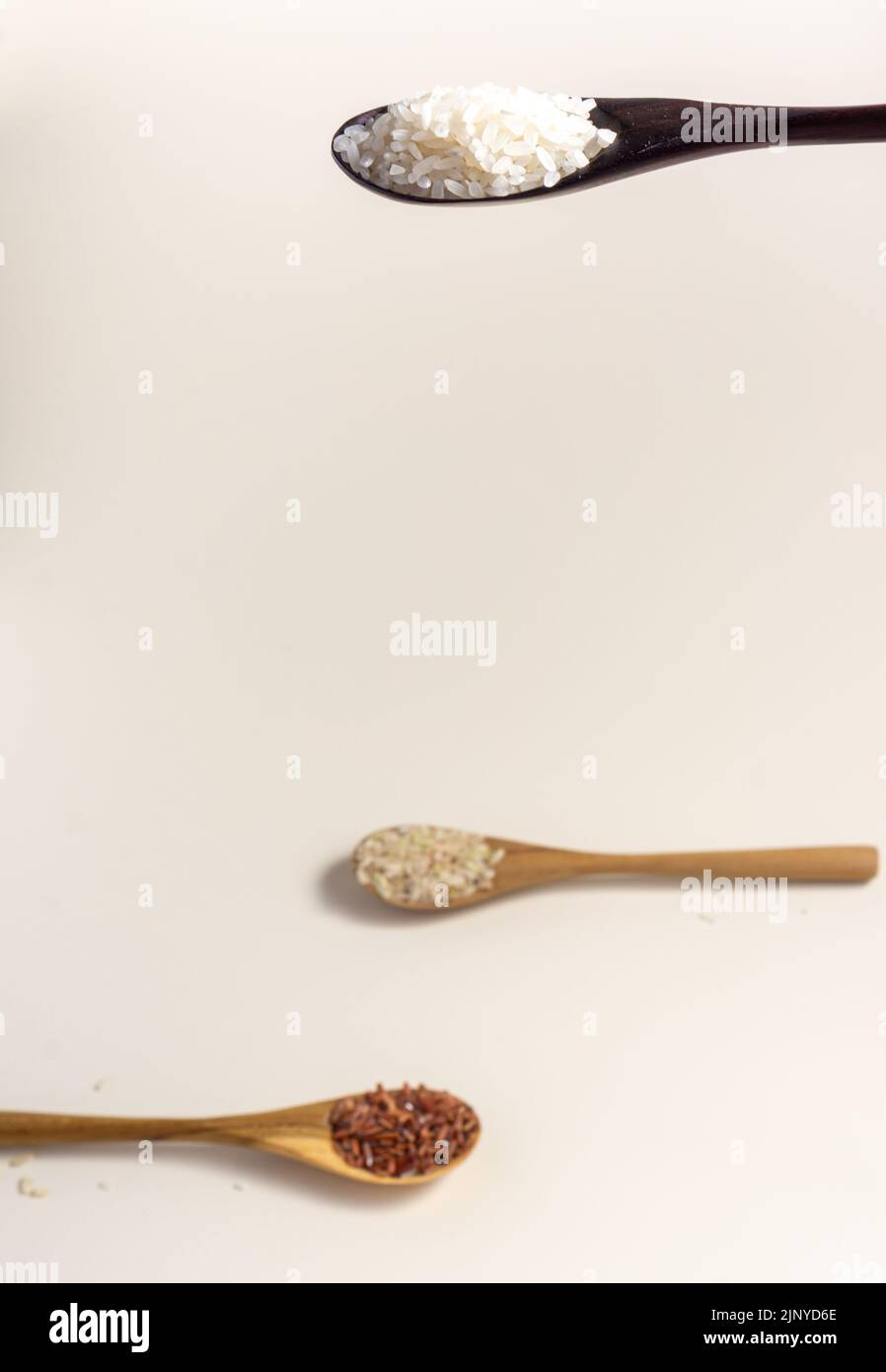 Raw and uncooked rice assortment in wooden spoon on white background ...
