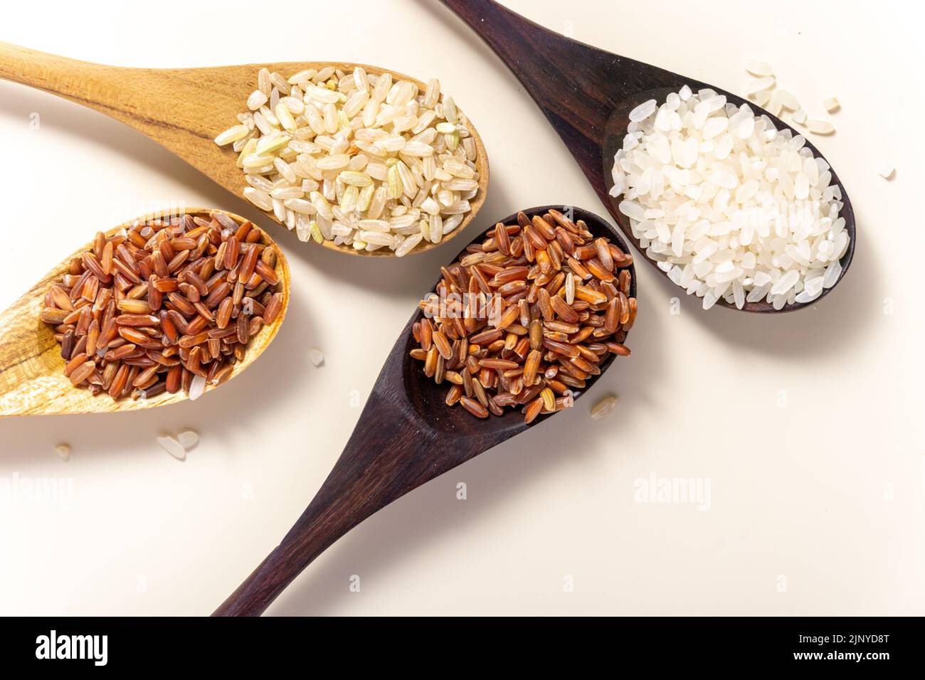 Raw and uncooked rice assortment in wooden spoon on white background ...