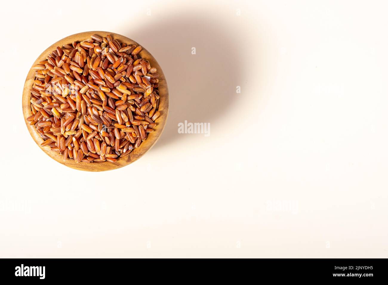 raw red rice in the wooden bowl, isolated on white background ...