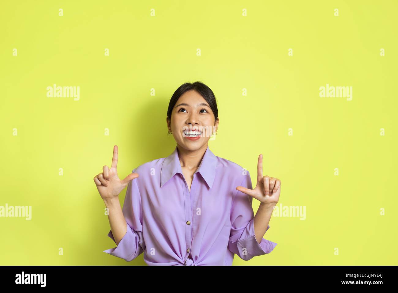 Japanese Female Pointing Fingers Up Standing Over Yellow Studio ...