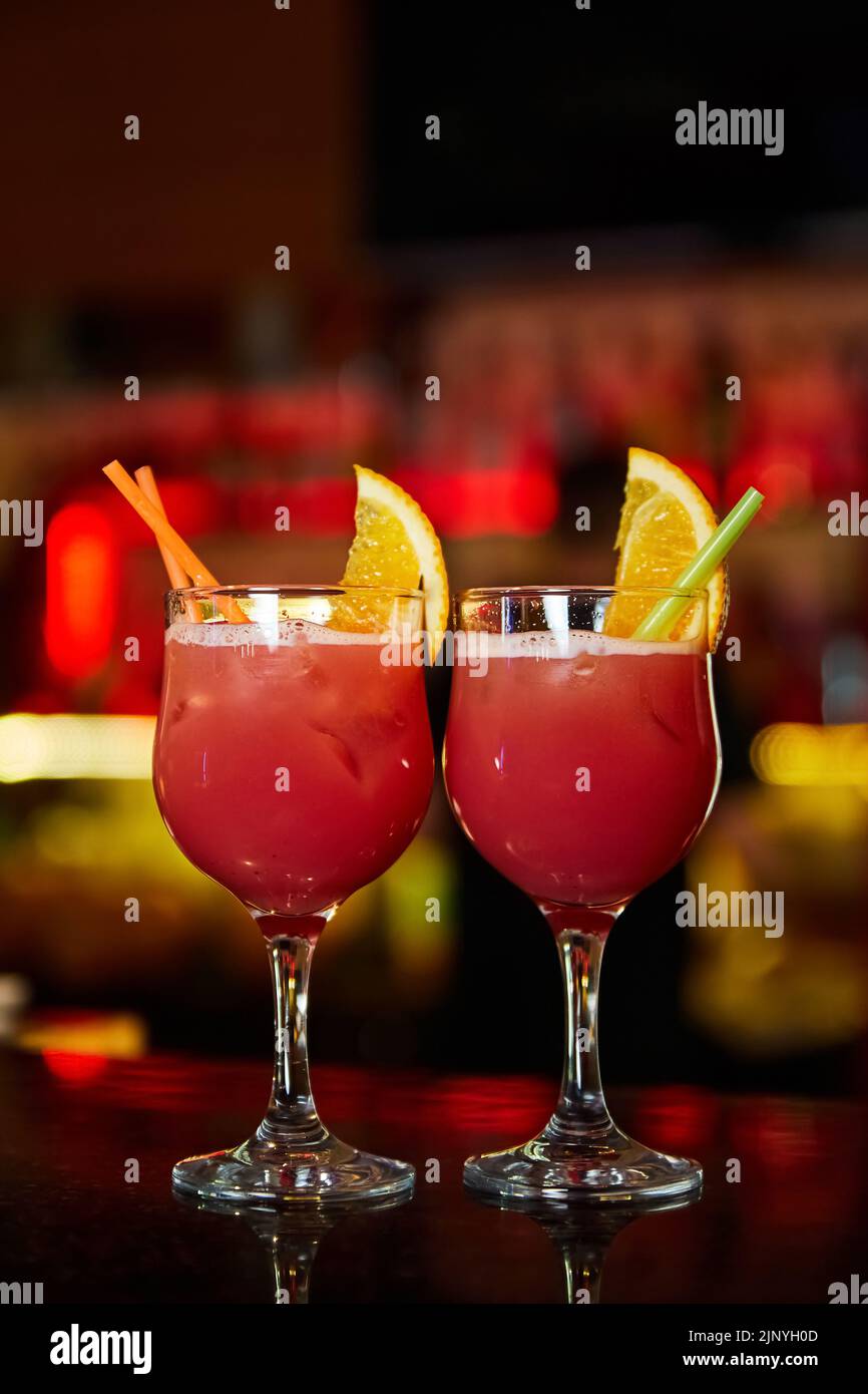 Red Alcoholic cocktails decorated with half slices of orange on the bar ...
