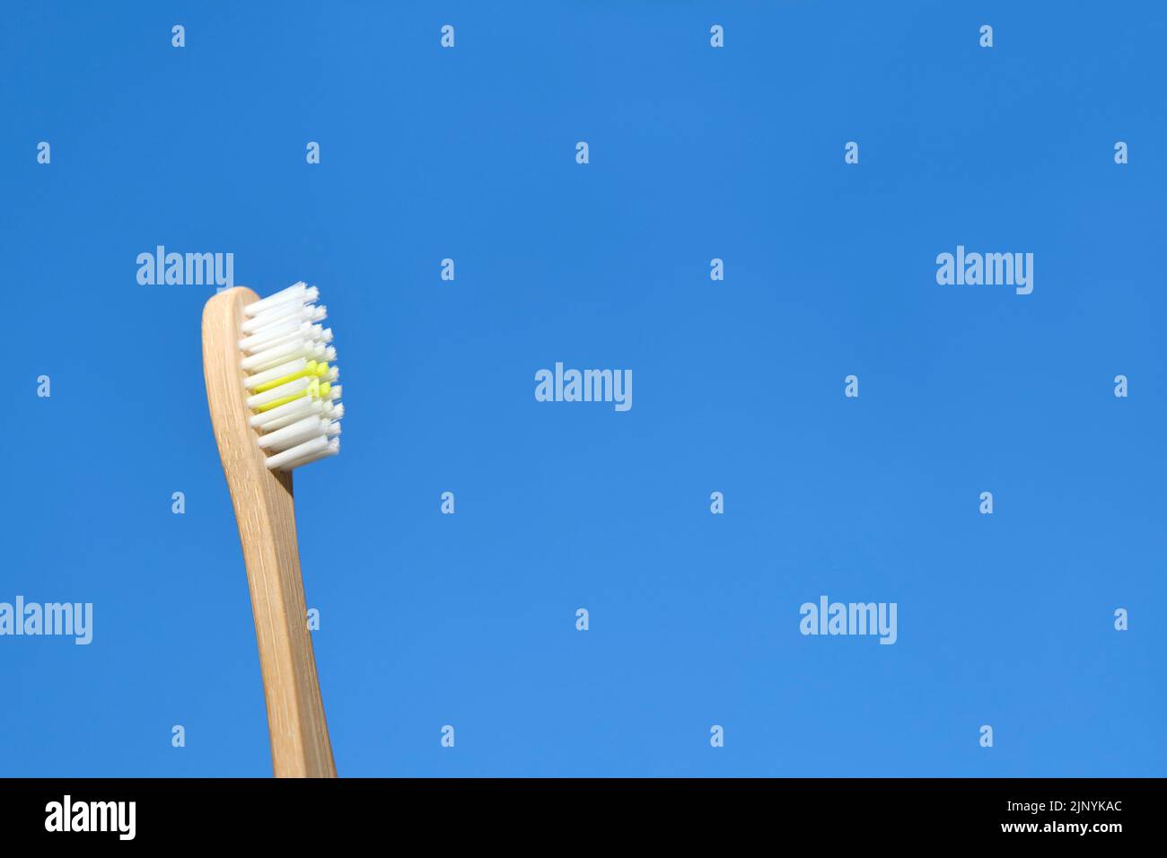 Ecological toothbrush made of bamboo against a background of blue sunny ...