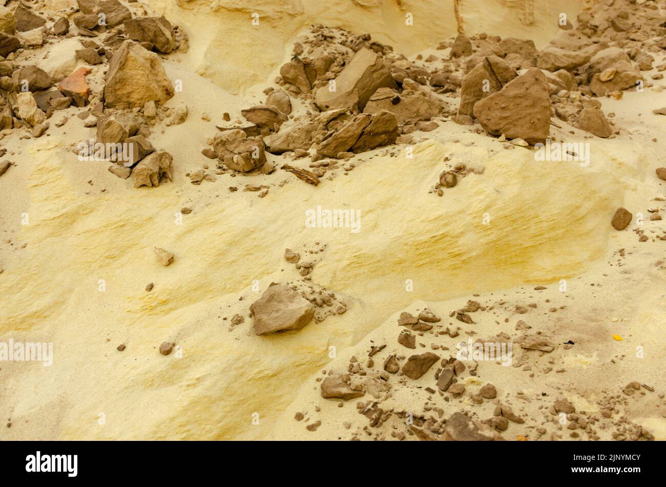 Weathered sand sculptures or formations with brown rock stones. Sand is ...