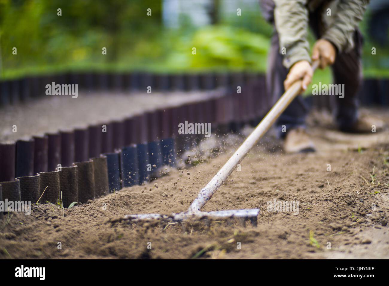 Farmer cultivating land in the garden with hand tools. Soil loosening ...