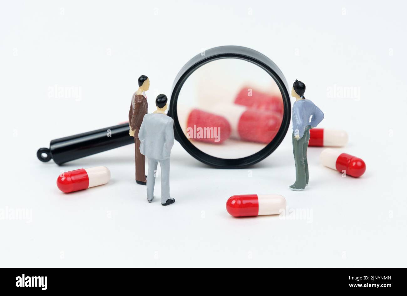 Three miniature figures of people look through a magnifying glass at ...
