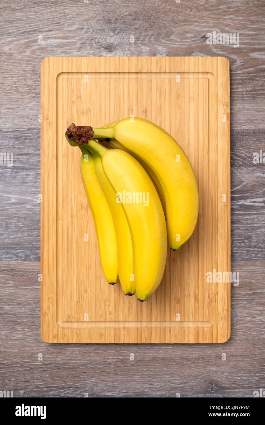 Branch of ripe bananas on a kitchen board, top view Stock Photo - Alamy