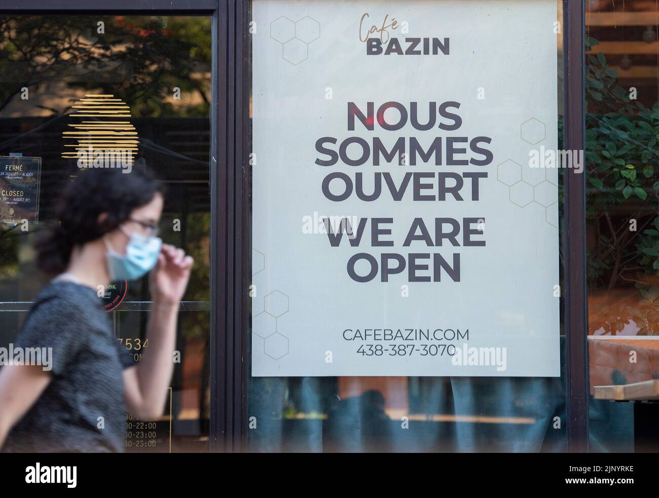 A woman walks by a bilingual sign for a cafe in the city of Westmount ...