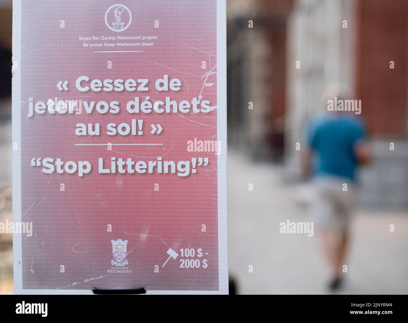 A man walks by a bilingual sign telling people to stop littering in the ...