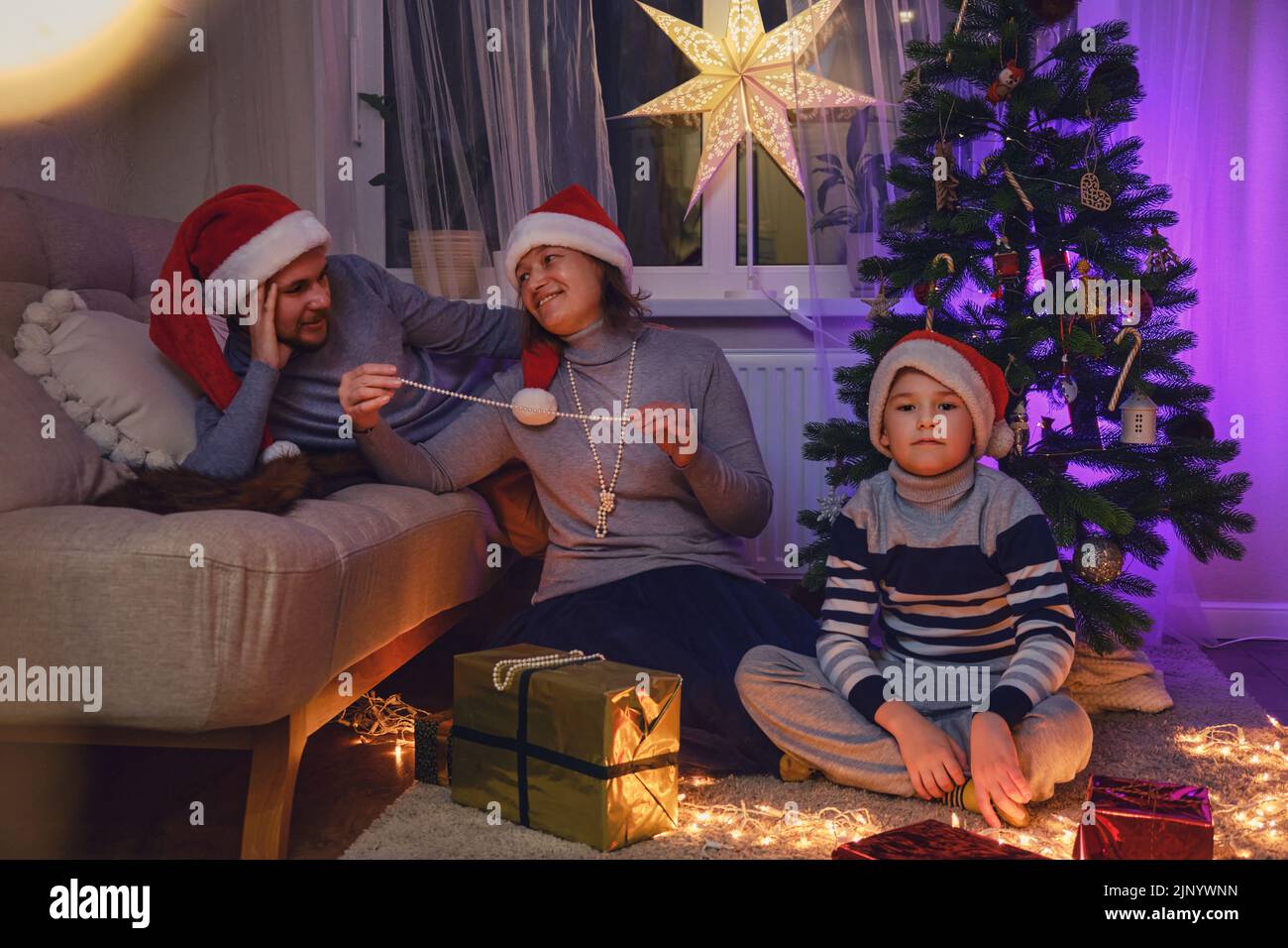 Happy family with gifts at the Christmas tree in the night light ...