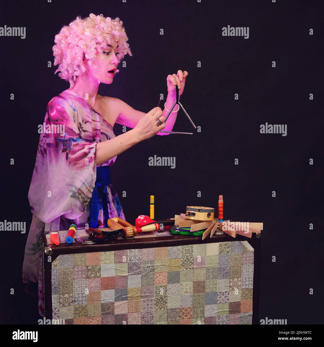 Happy women in funny wigs give a musical performance on a studio black ...