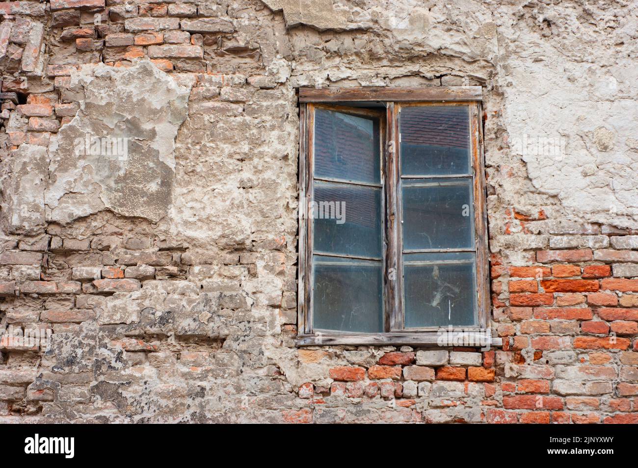Exterior of old crumbling building has a single window with a wood ...
