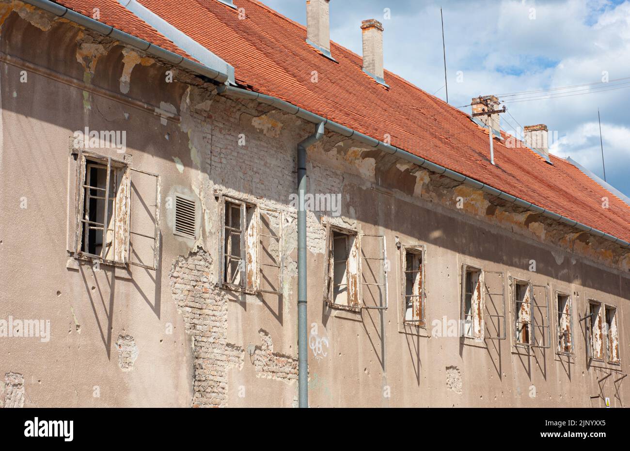 Windows line the outer wall of a worn brick & plaster citadel building ...