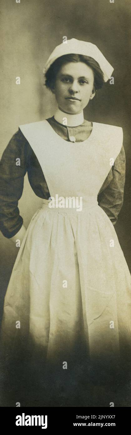 Early 20th century portrait of nurse in uniform standing and posing for ...