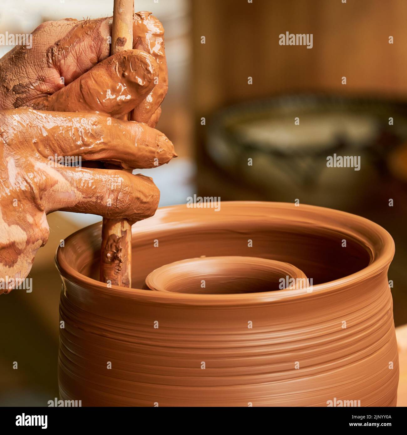 A man in old medieval Byzantine clothes sits behind a vintage potter's ...