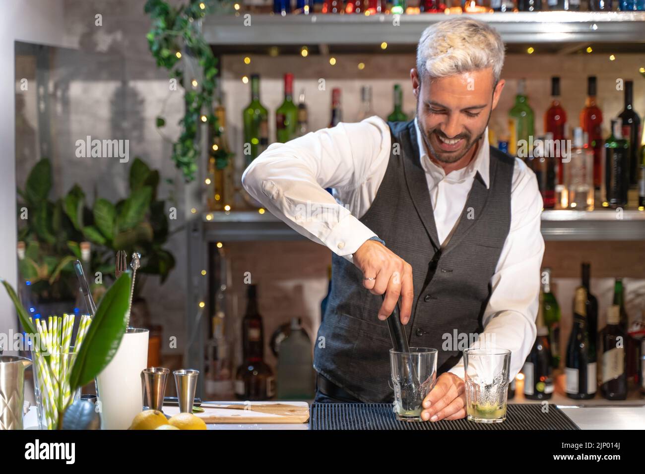 Elegant barman making cocktail Mojito in night club adding ingredients ...