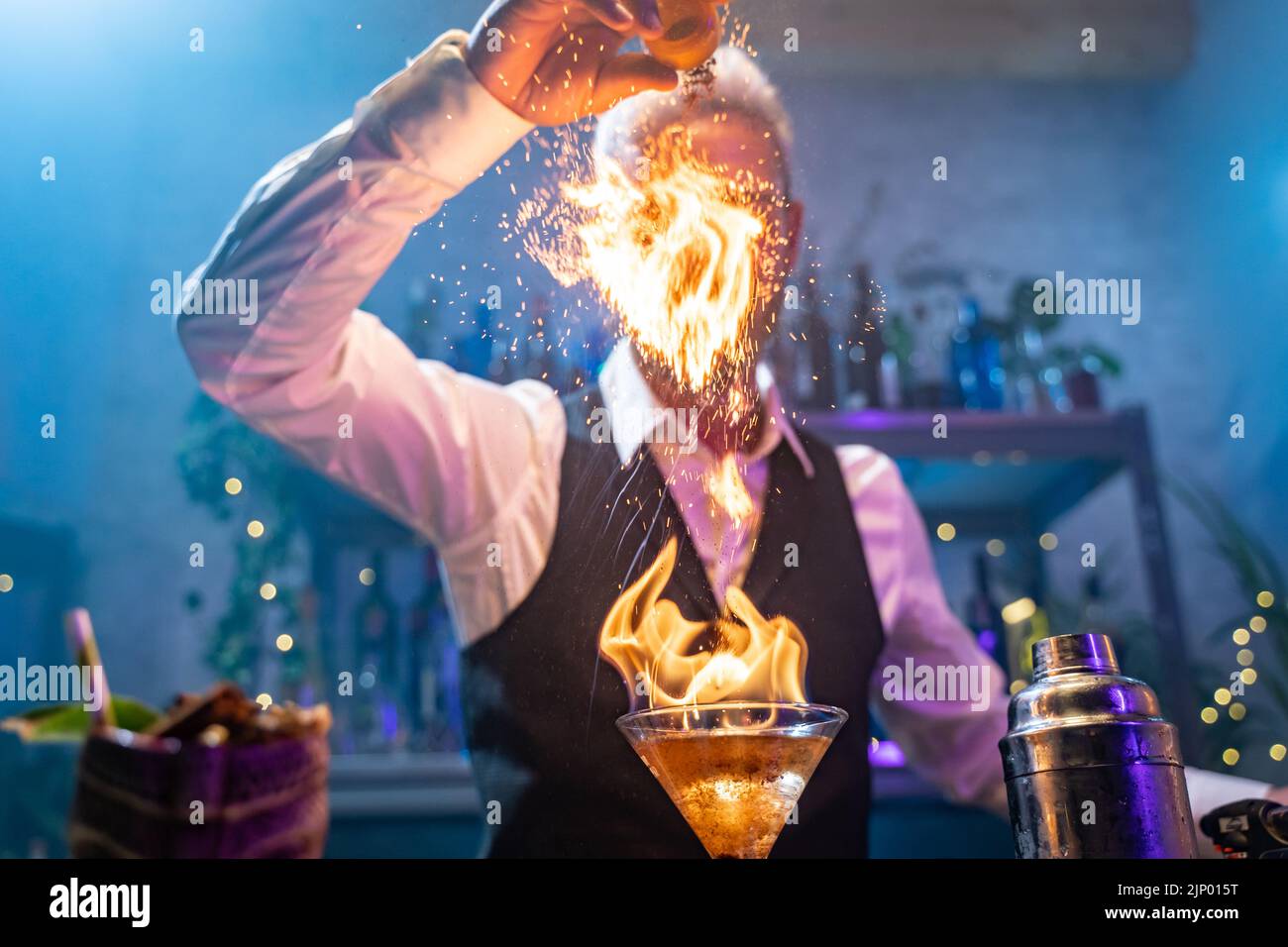 Bartender making a fire flame cocktail in a elegant night club party ...