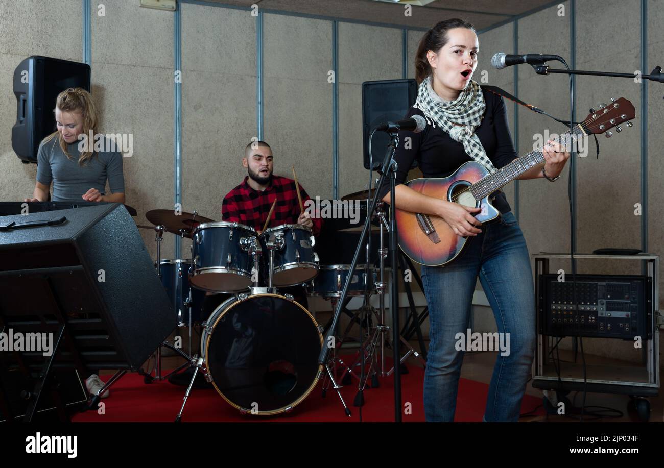 Attractive guitar player and singer with band Stock Photo - Alamy