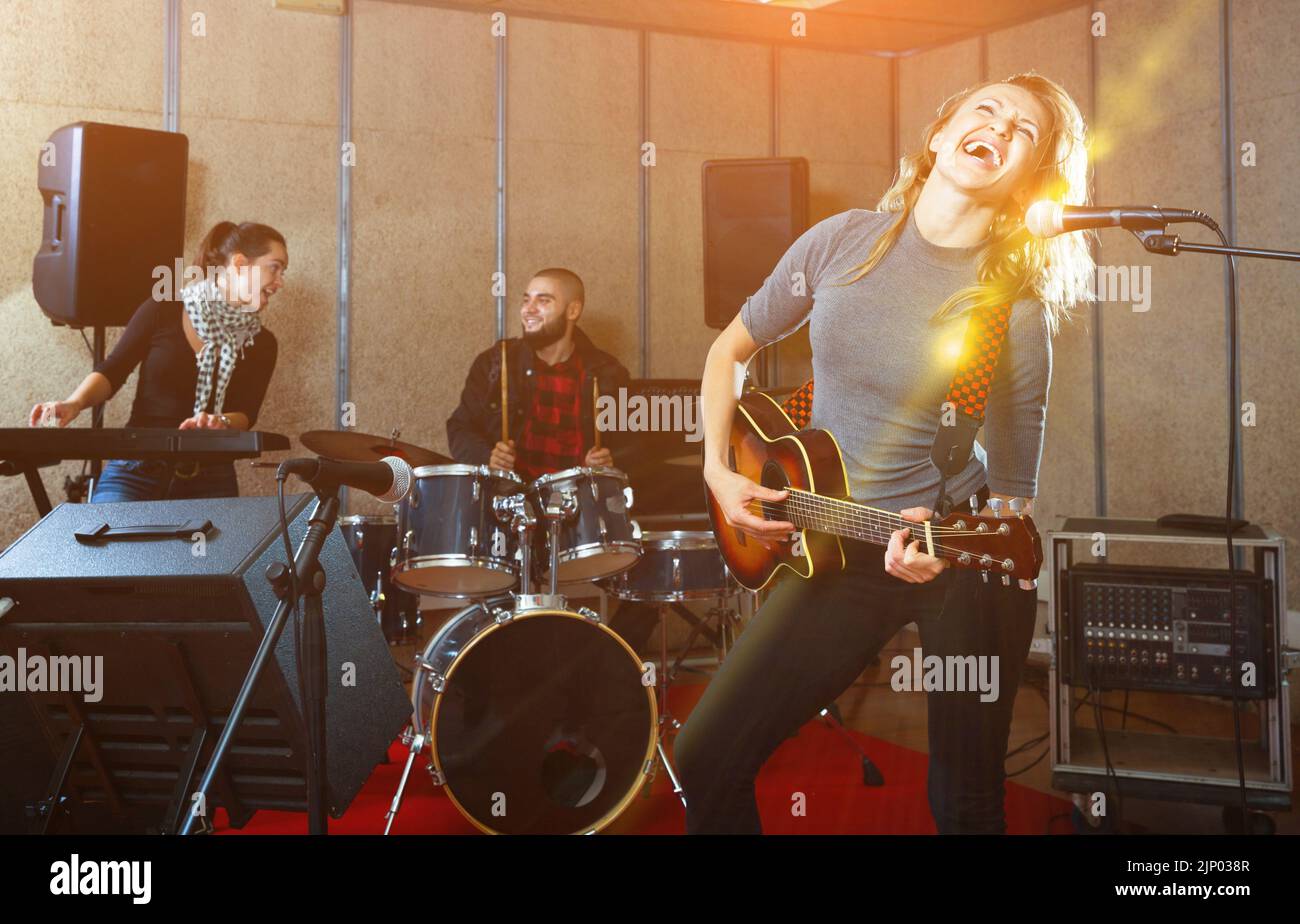 Attractive female soloist playing guitar and singing with her mu Stock ...
