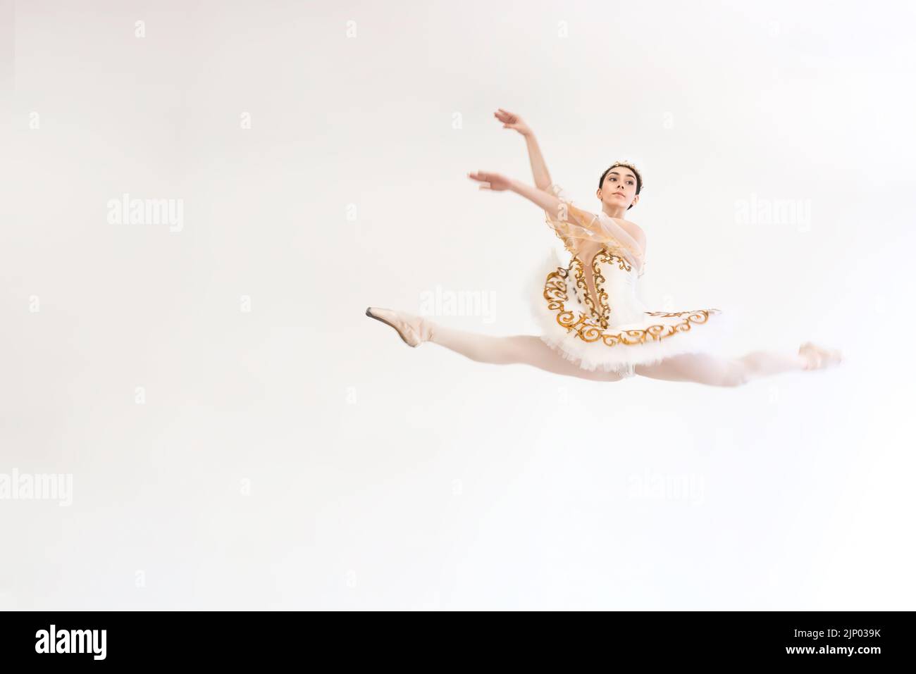 A young charming ballerina does ballet exercises in a jump against a ...