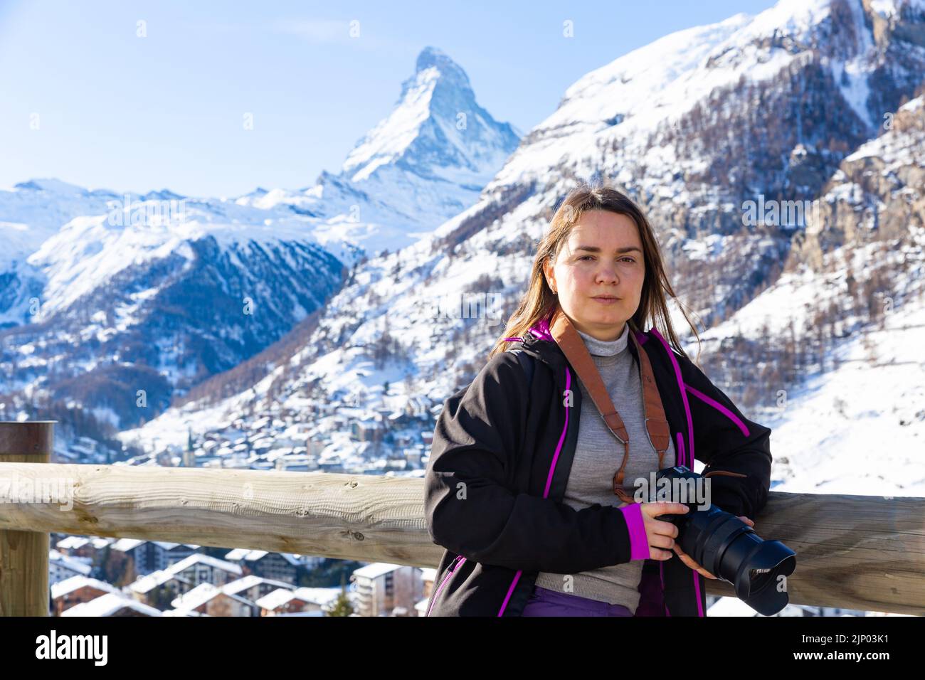 Female traveler with camera enjoying hiking in Swiss Alps in winter ...