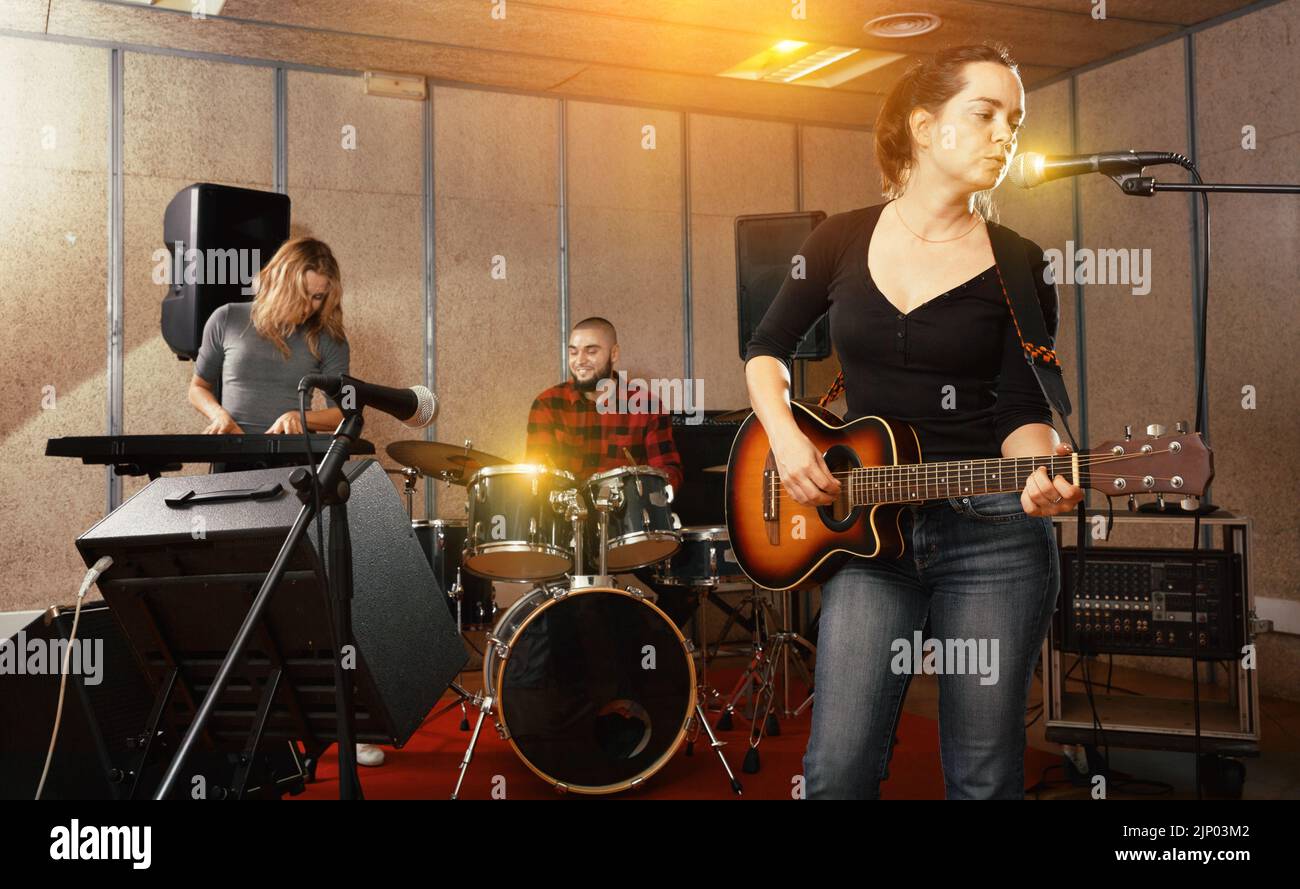 Attractive female soloist playing guitar and singing with her mu Stock ...