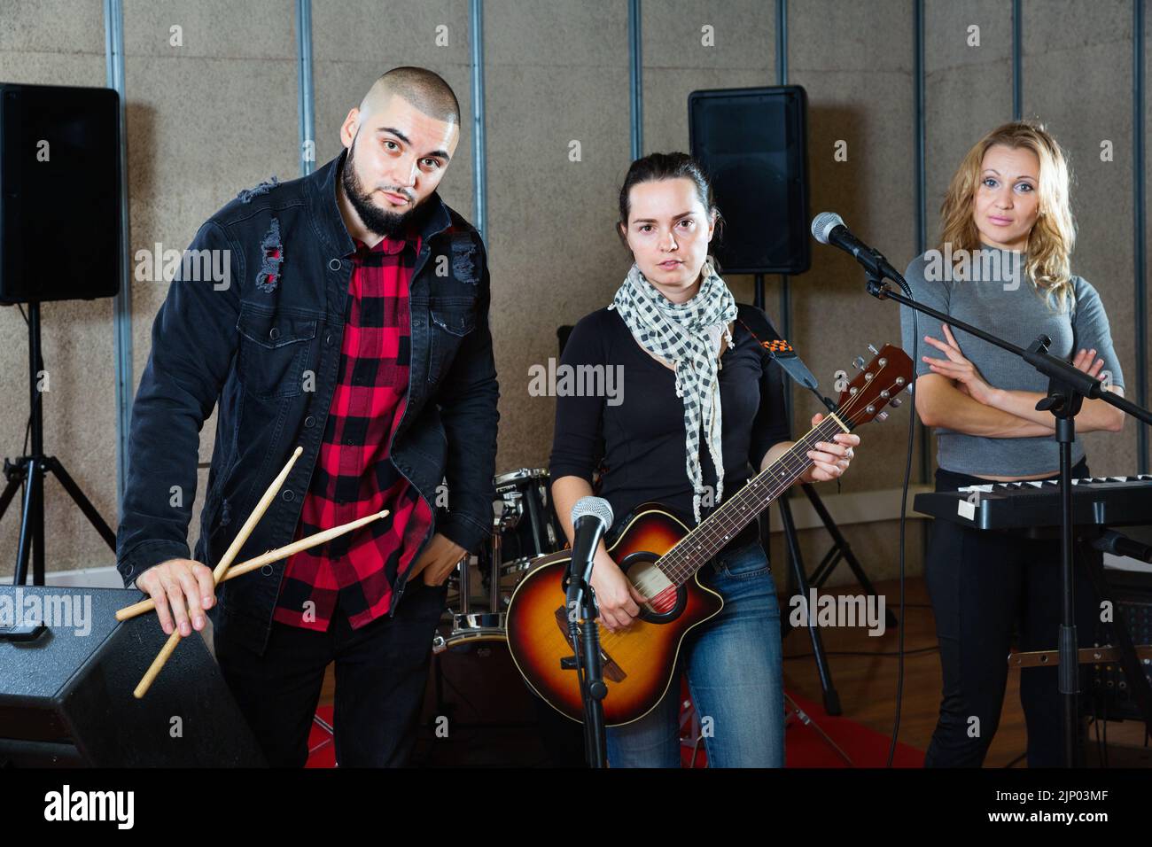 Three bandmates posing together with musical instruments in rehearsal ...