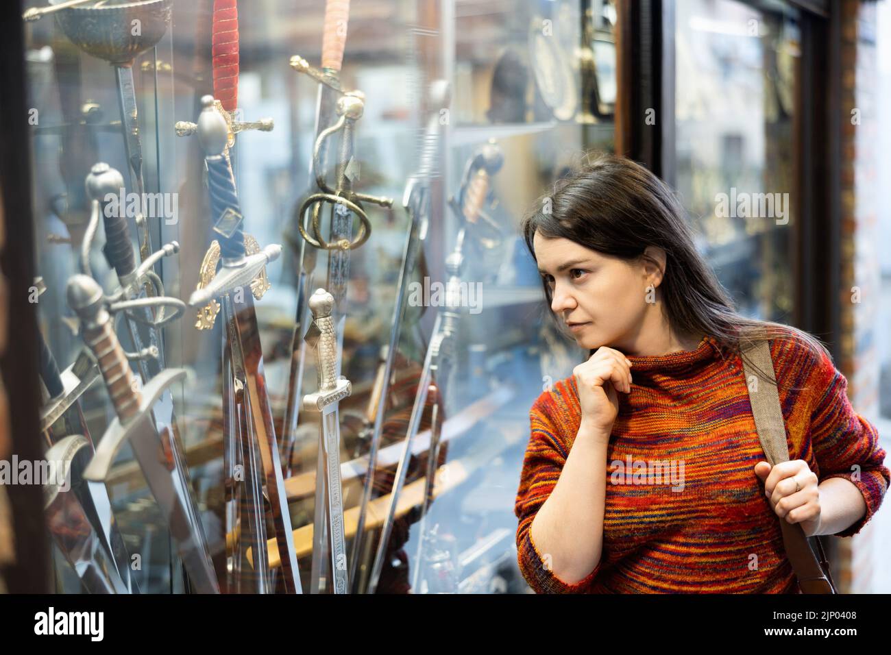 Female traveler viewing at handmade forged swords in gift shop of ...