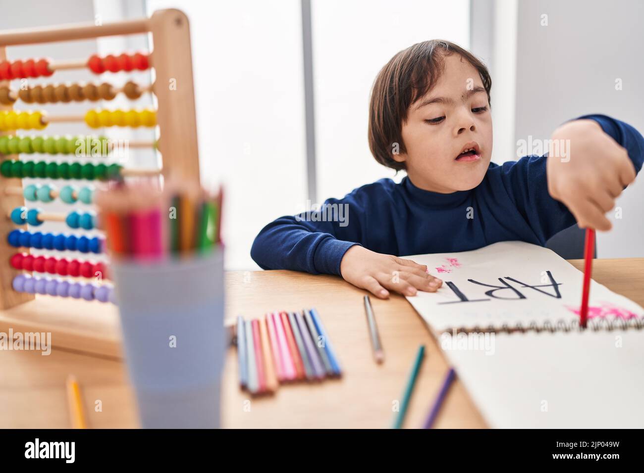 Down syndrome kid drawing on notebook at school Stock Photo - Alamy