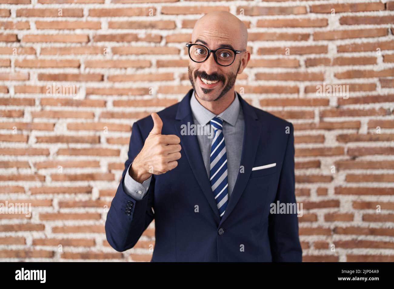 Bald man with beard wearing business clothes and glasses doing happy ...