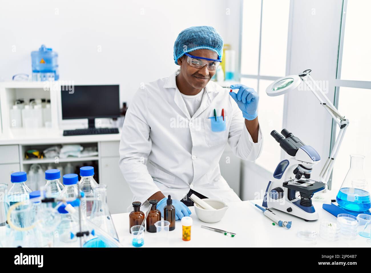 Young south east man wearing scientist uniform holding pill at ...