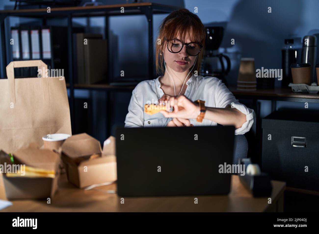 Young beautiful woman working using computer laptop and eating delivery ...