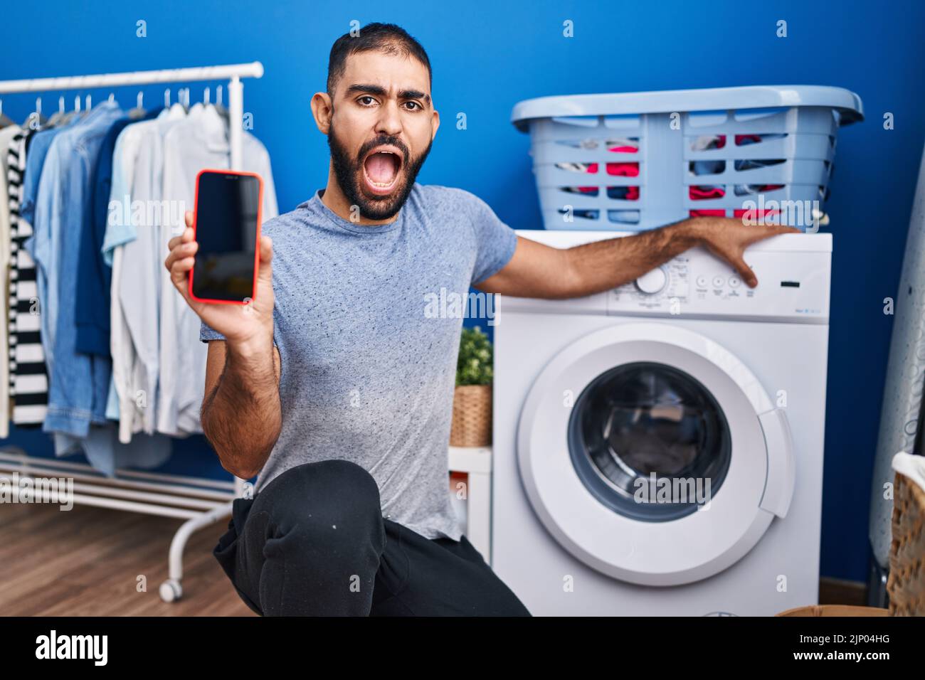 Middle east man with beard showing smartphone screen and washing ...