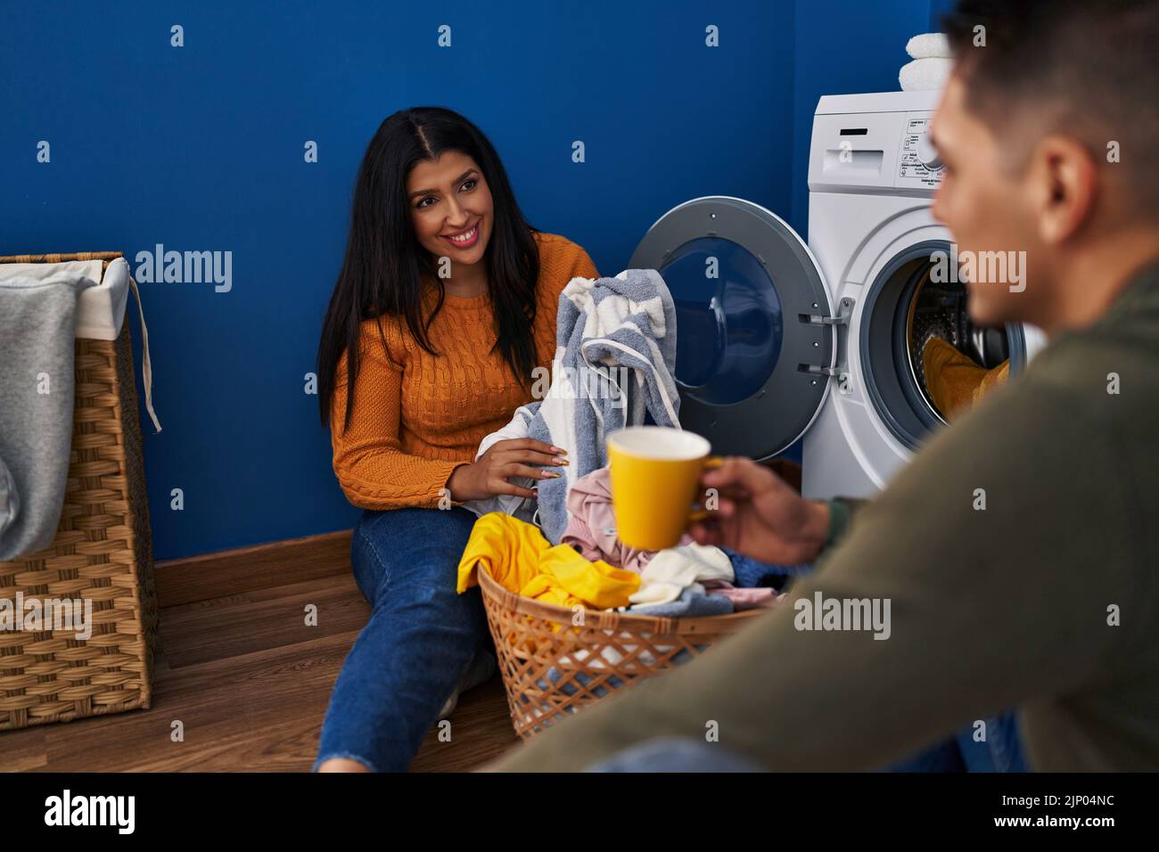 Man and woman couple washing clothes drinking coffee at laundry room Stock Photo - Alamy