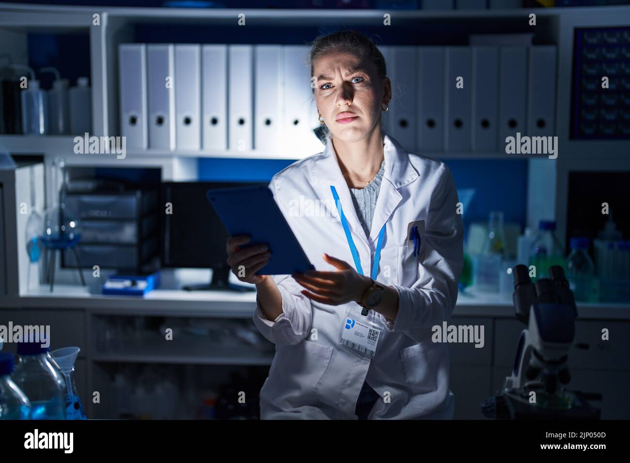 Beautiful blonde woman working at scientist laboratory late at night ...