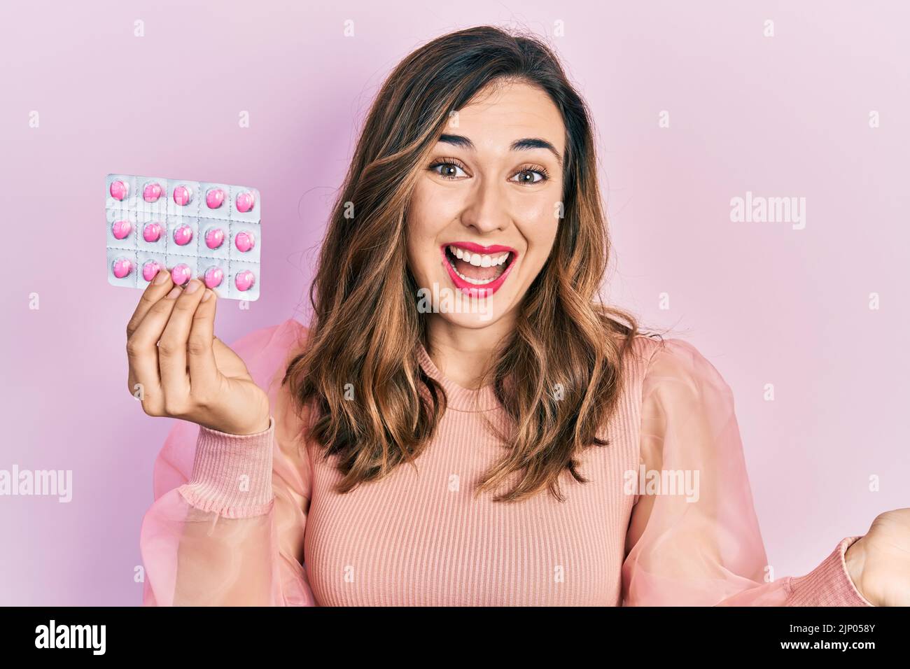 Young hispanic girl holding pills celebrating achievement with happy ...