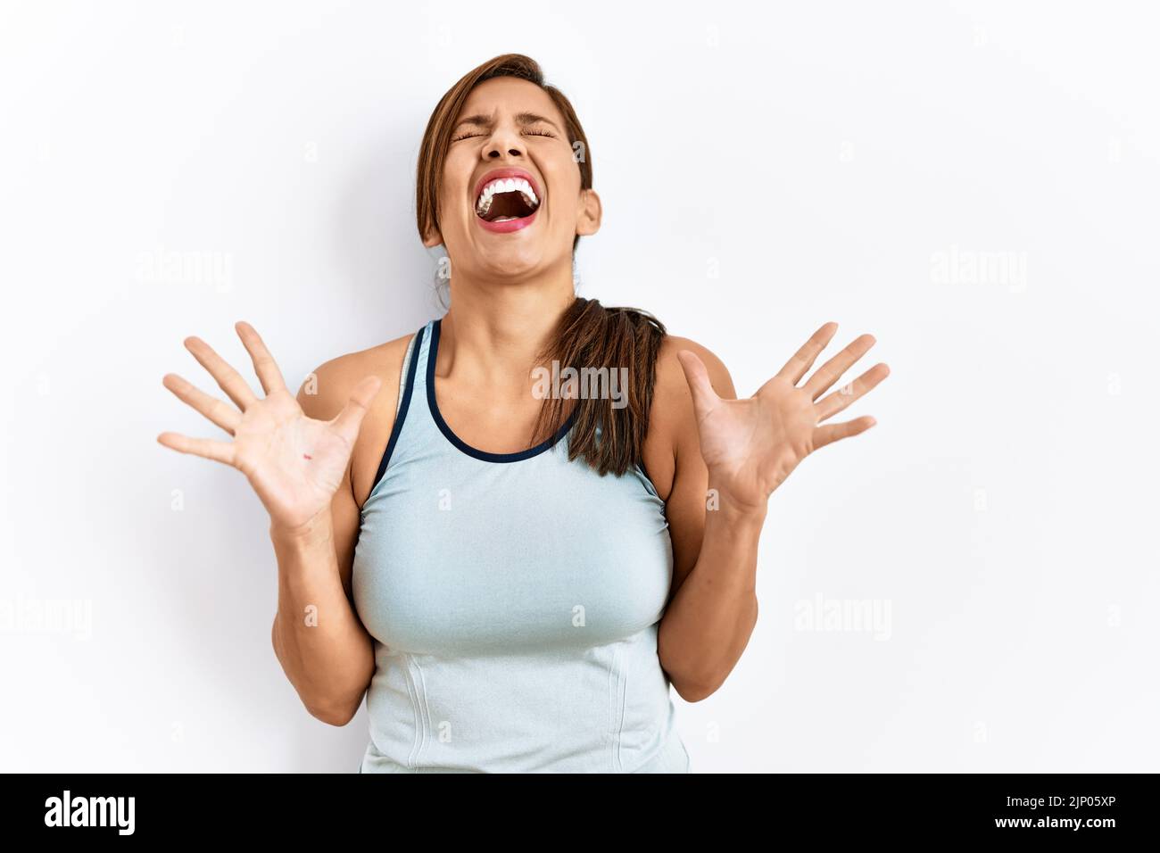 Young latin woman wearing sporty clothes over isolated background ...