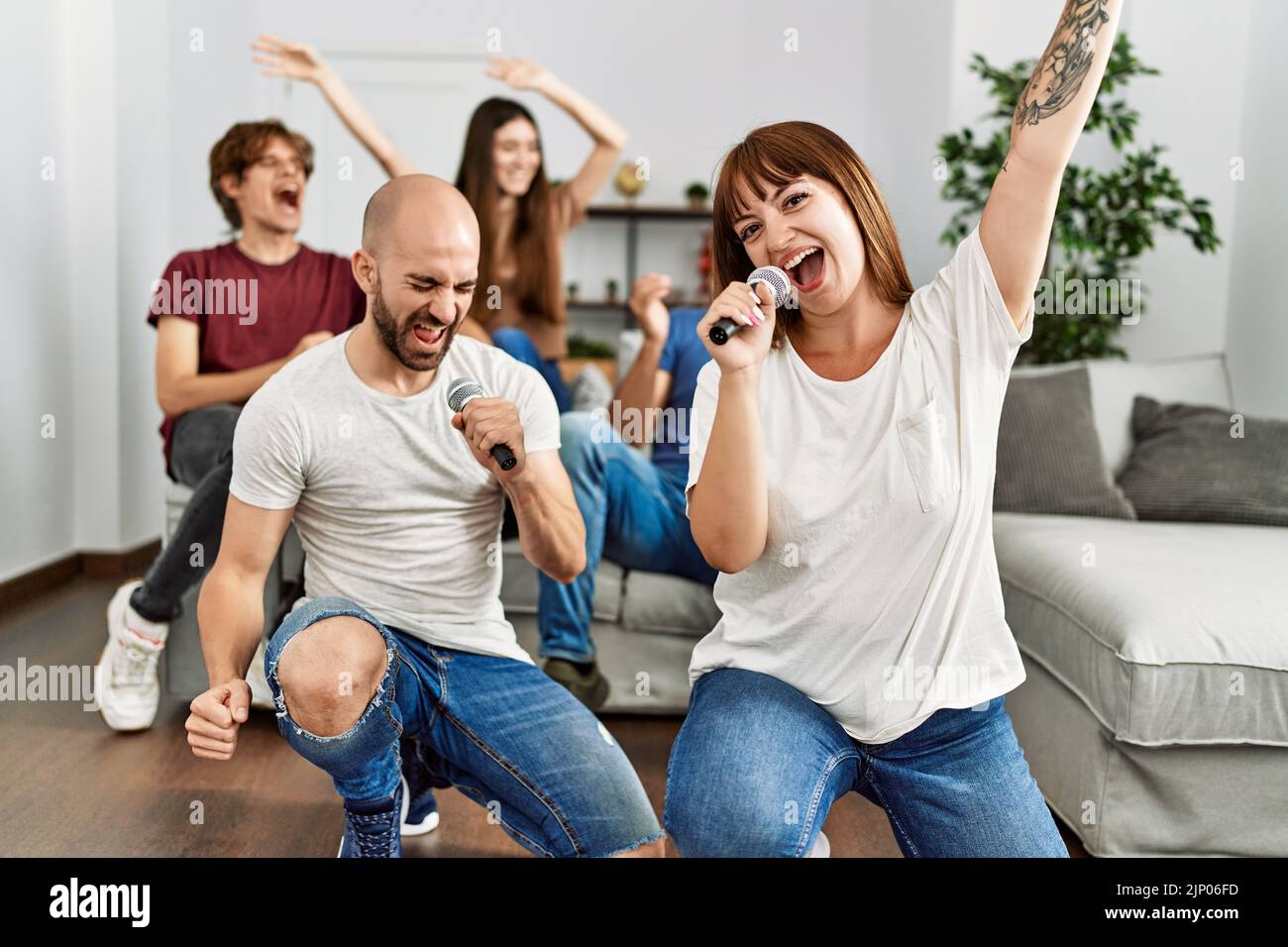 Group of young friends having party singing song using microphone at ...