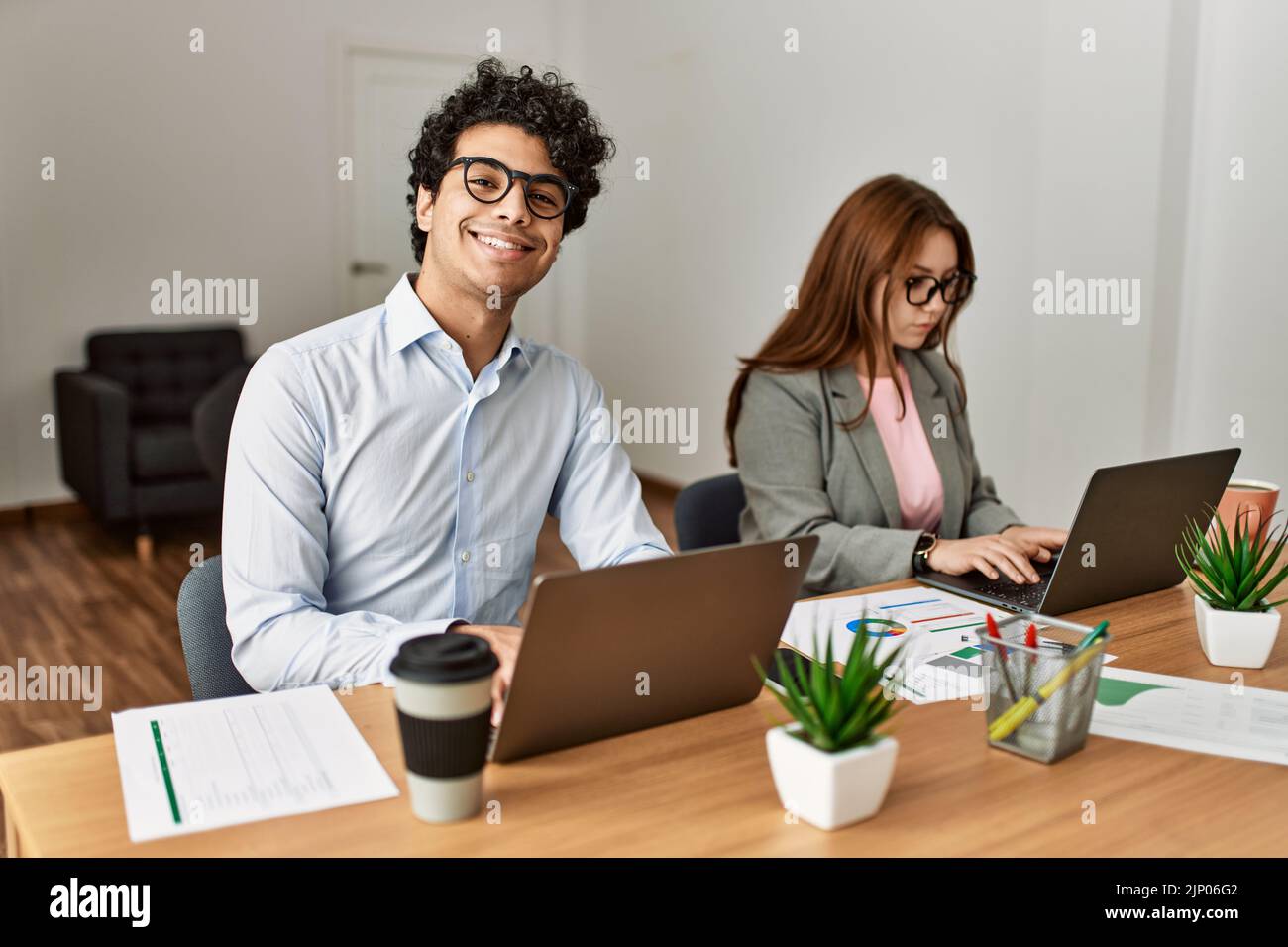 Two business workers smiling happy working using laptop at the office ...