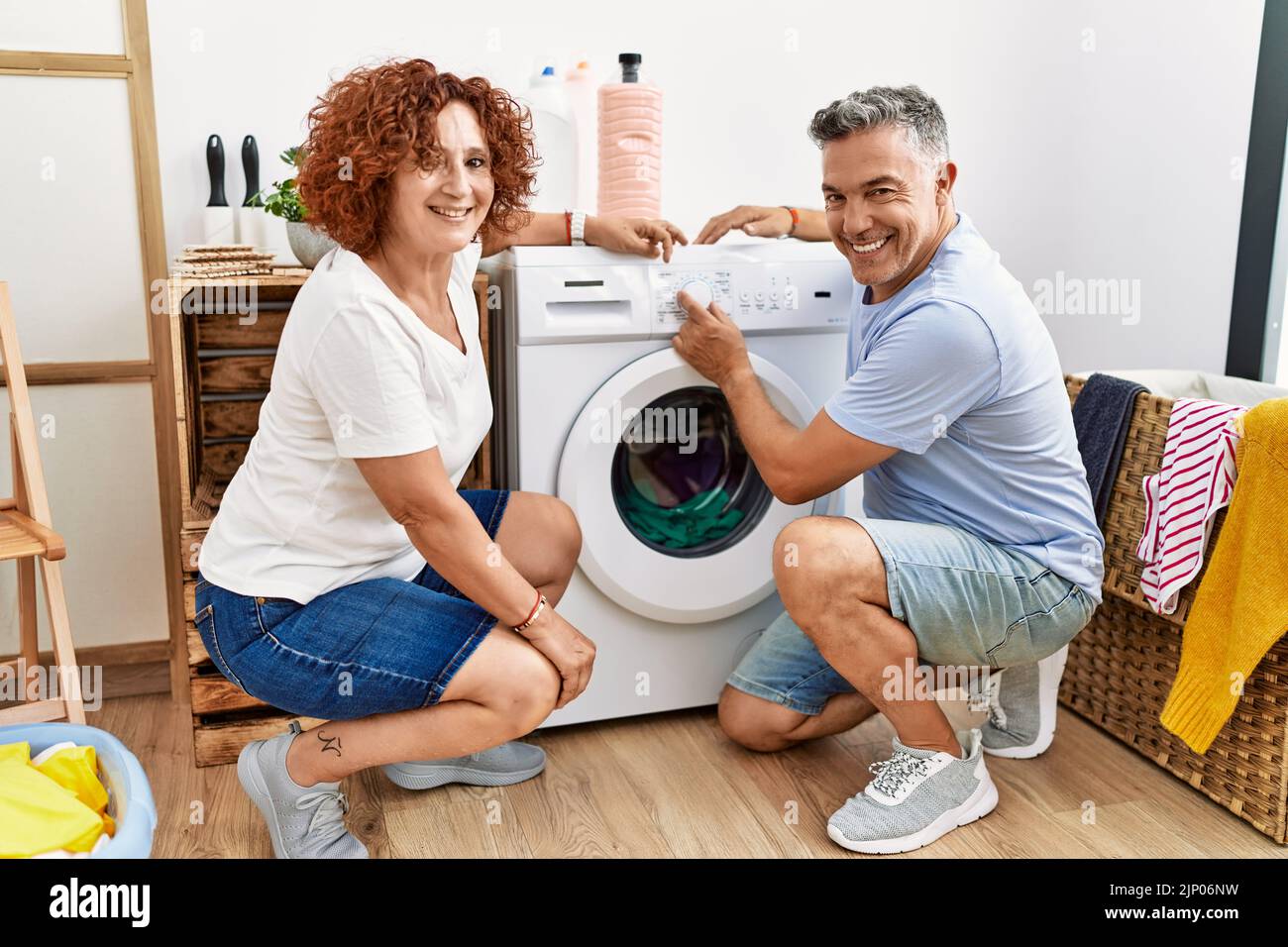 Middle age man and woman couple smiling confident turning on washing ...