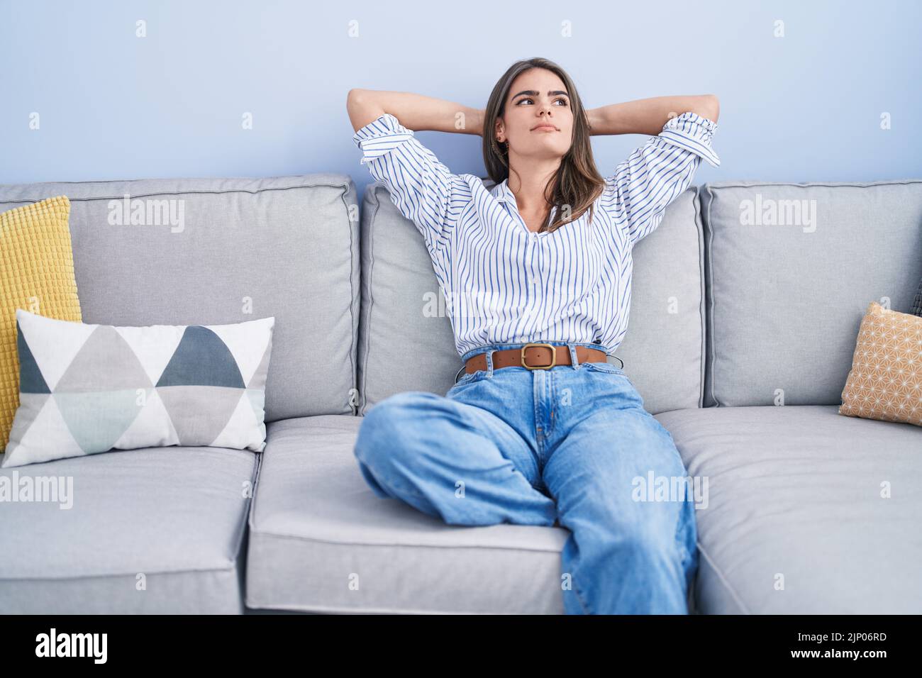 Young woman relaxed with hands on head sitting on sofa at home Stock ...