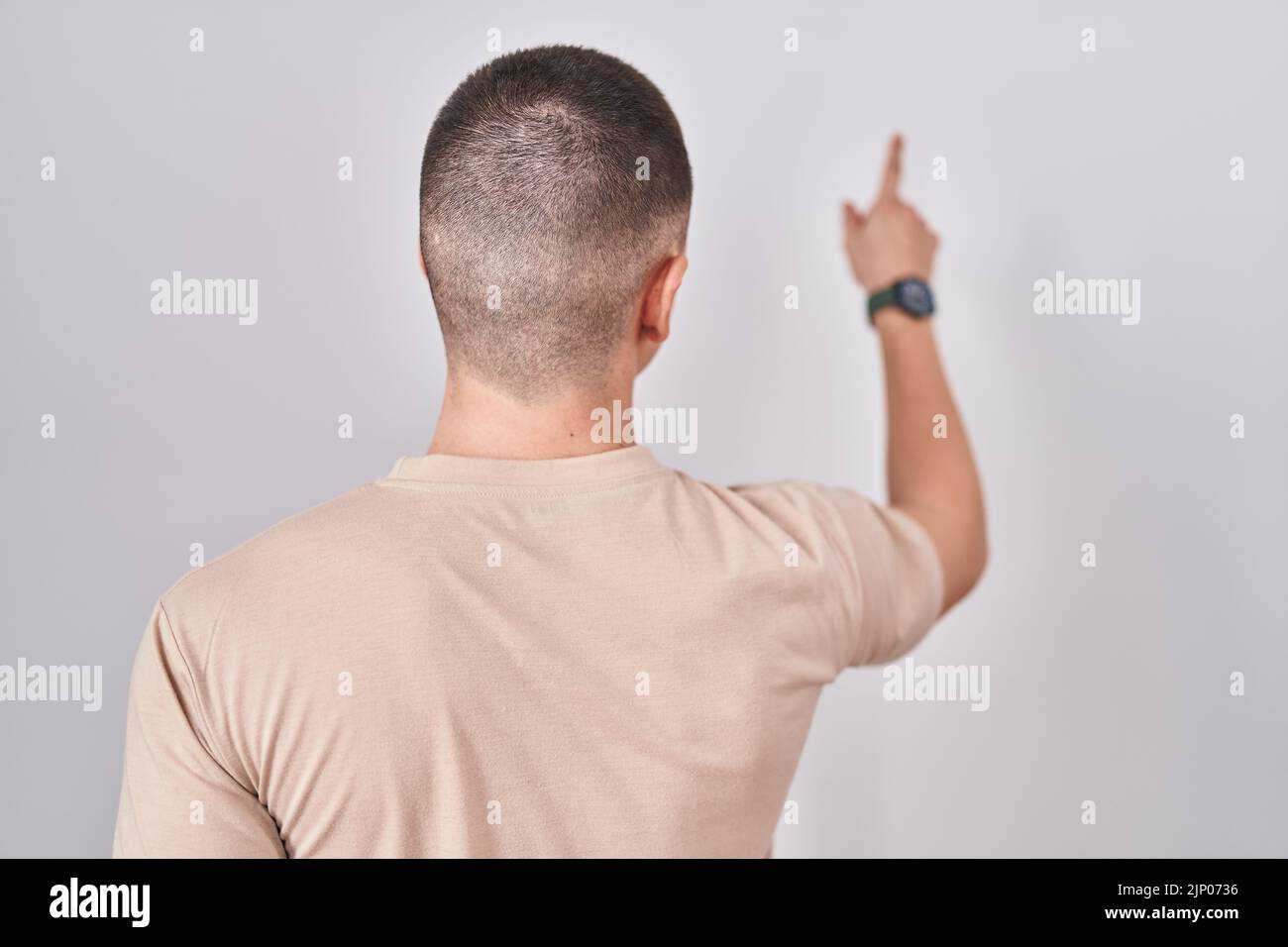 Young man standing over isolated background posing backwards pointing ...